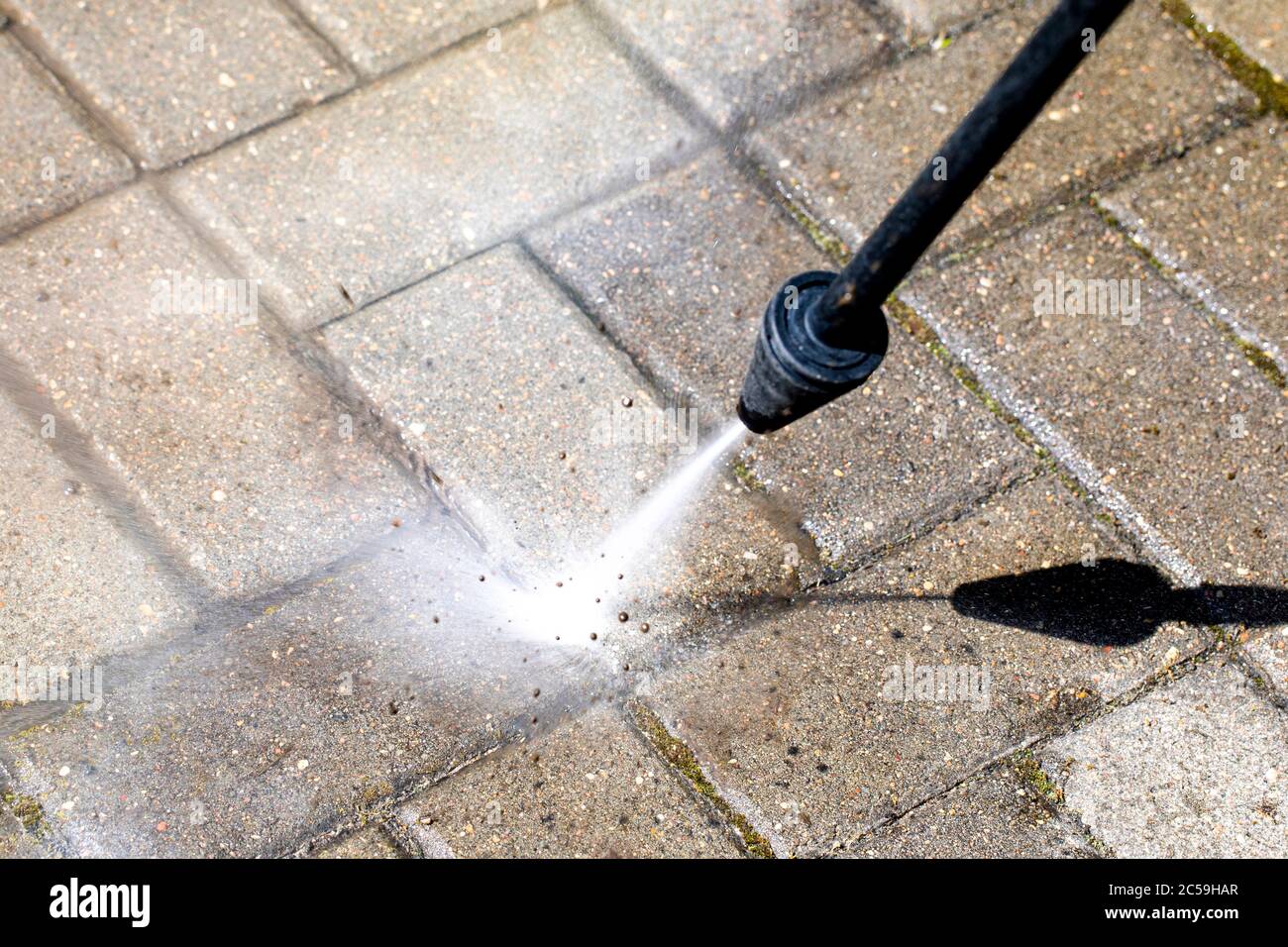high-pressure washer cleans concrete stones of garden line in country ...