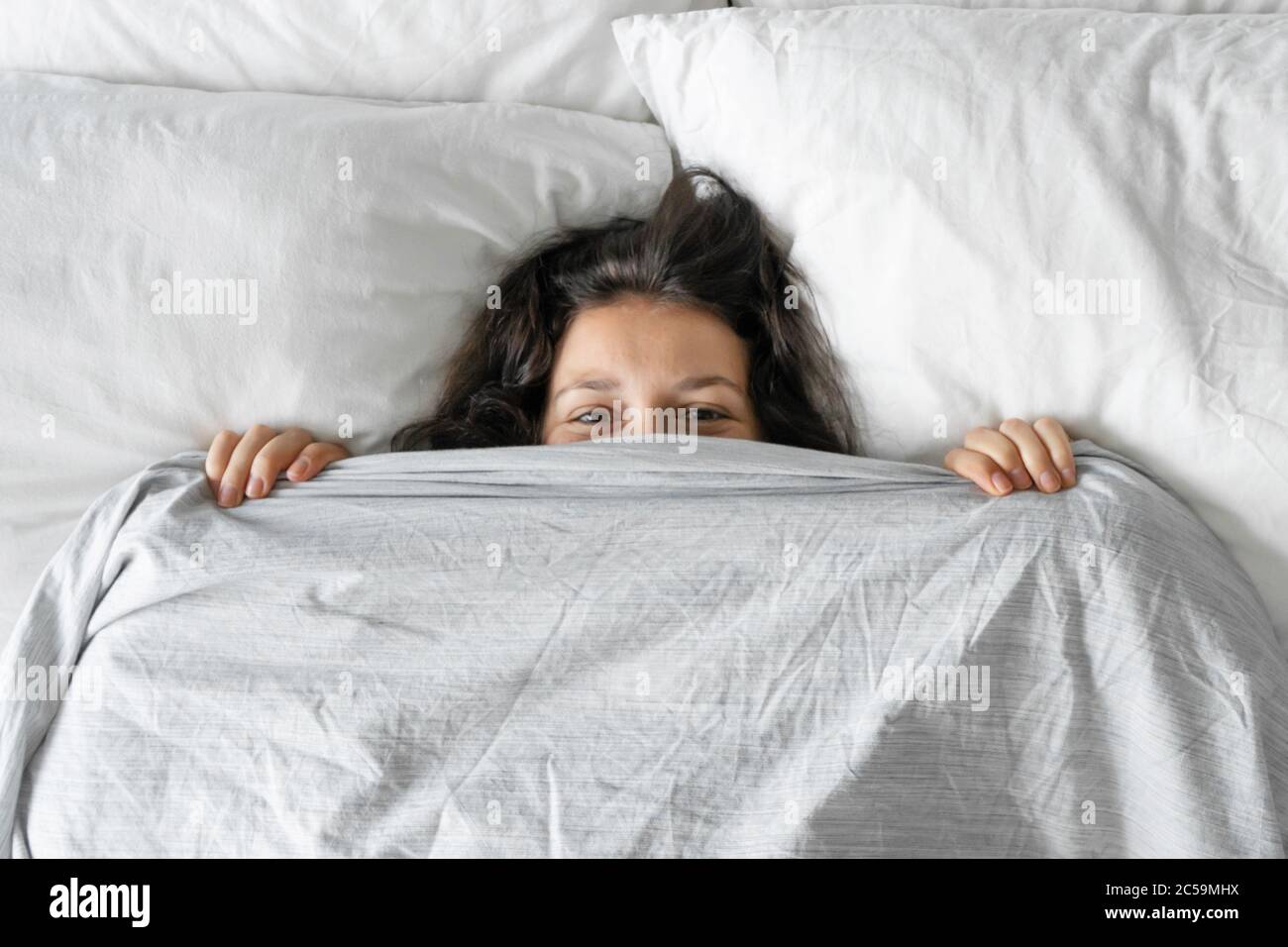 The girl does not want to get out of bed in the morning. Hiding in a ...