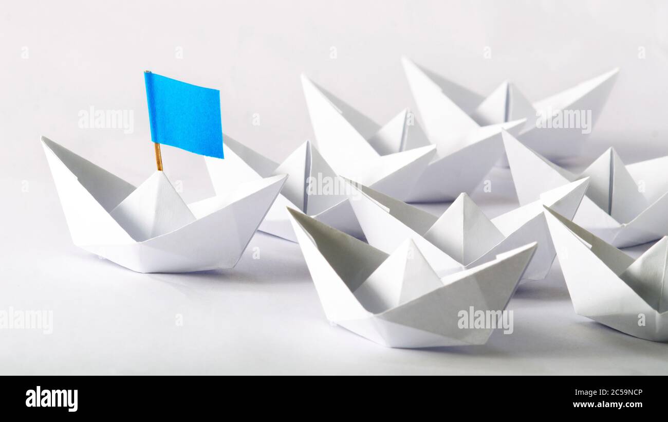 Leadership concept. Blue flag Origami White Paper boat (ship) leading ...
