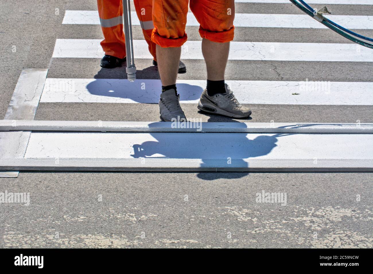 Workers are painting a pedestrian crossing in a city street Stock Photo ...