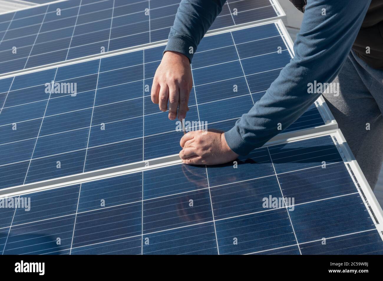 High angle shot of a male working on adjusting solar panels on a roof ...