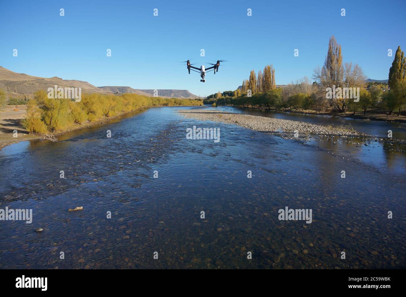 Aerial shot of a drone flying over a lake surrounded by trees ay ...