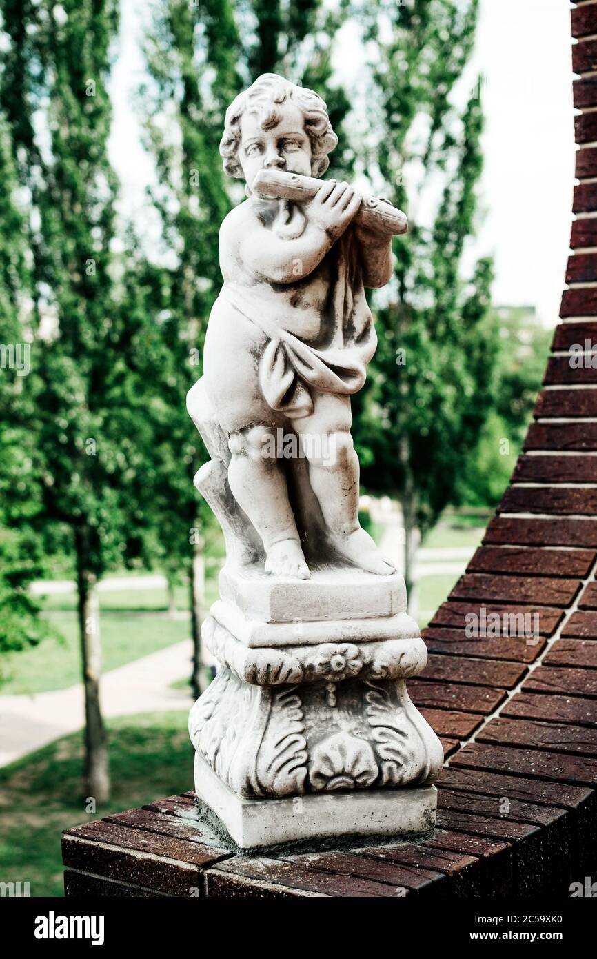 Statue of a boy on a brown stone wall Stock Photo - Alamy