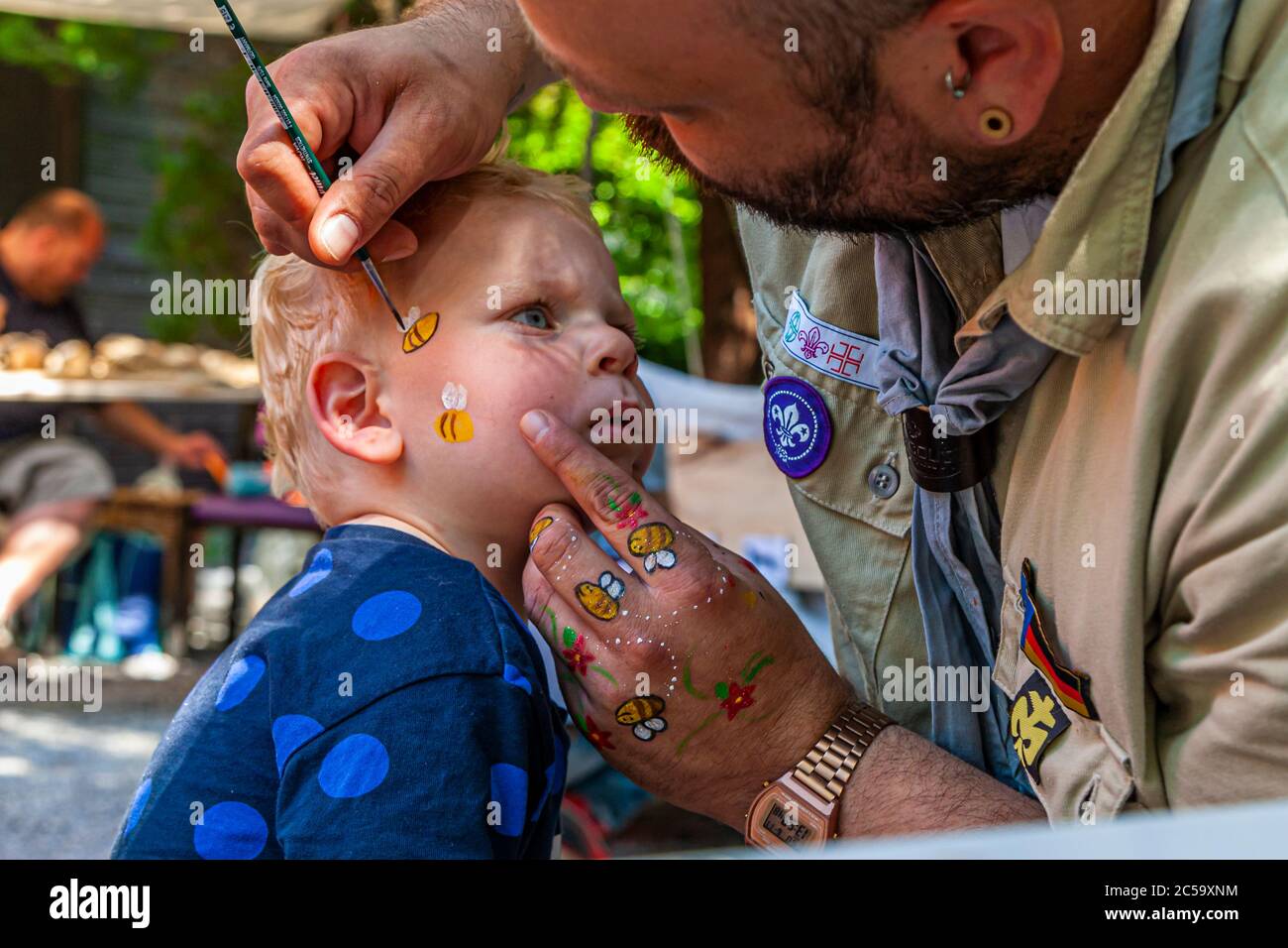 A little girl gets bees painted on her face. Children Face Painting in ...