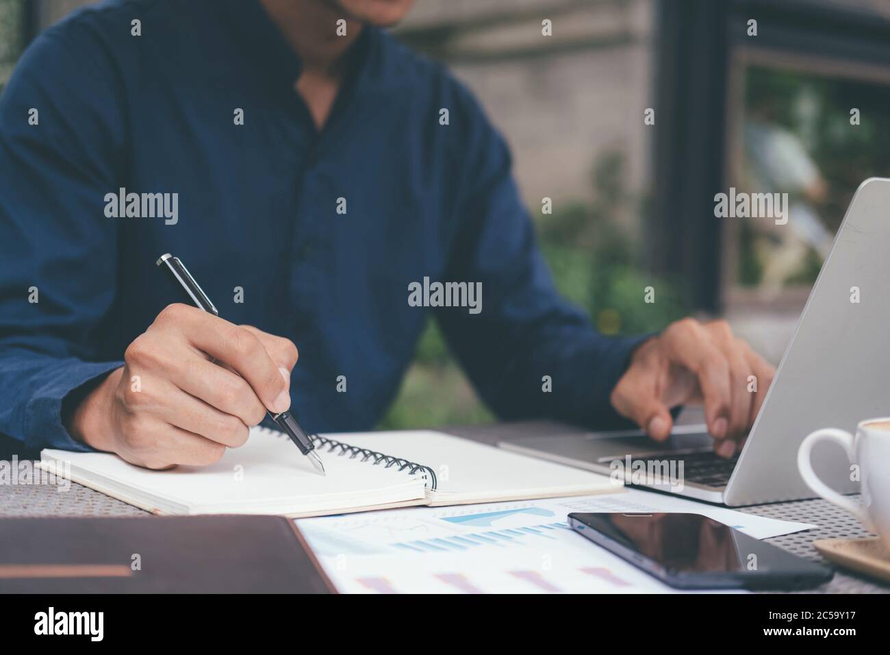 Closeup businessman writing hand and using computer outside the office ...