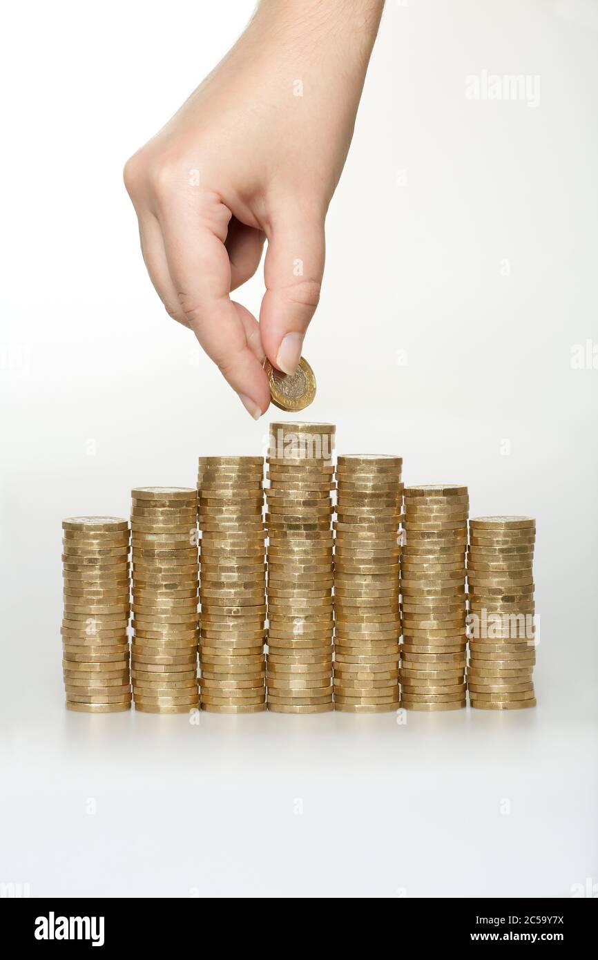 Photograph of a woman's hand placing a £1 coin on stacks of new uk £1 ...