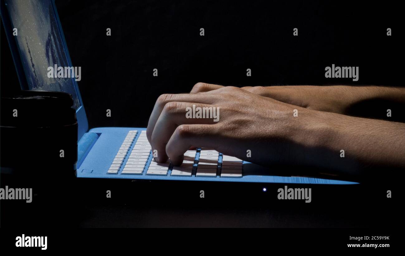 Closeup shot of male hands typing on a blue laptop with a white ...