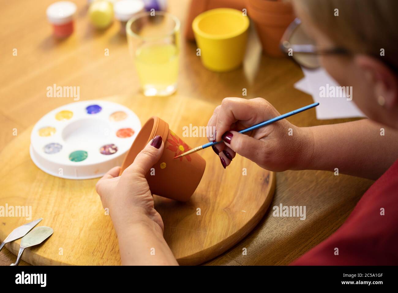 close-up of women's hands painting flower pot with paints hobby of ...