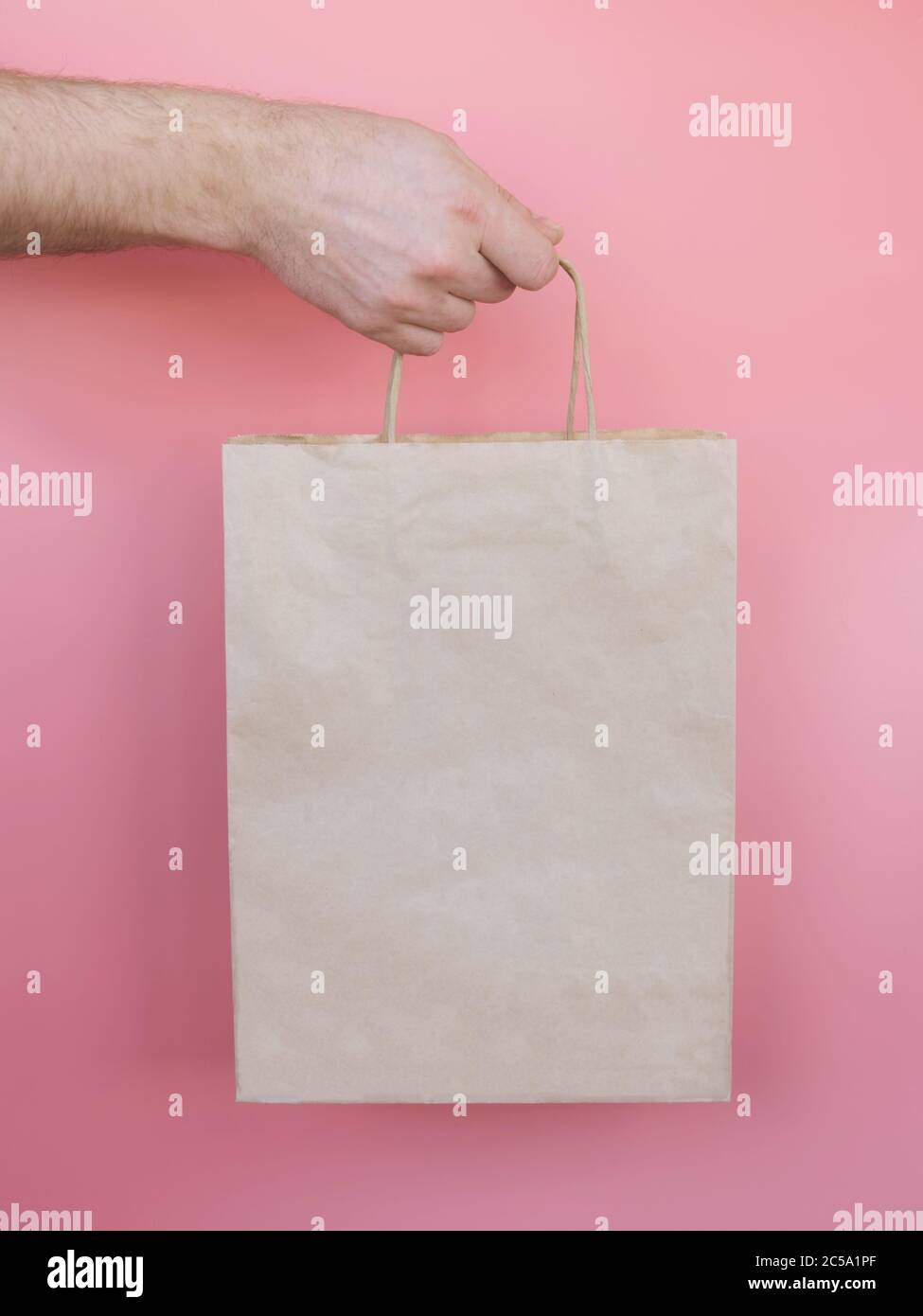 Man holding paper bag on pink background Stock Photo - Alamy
