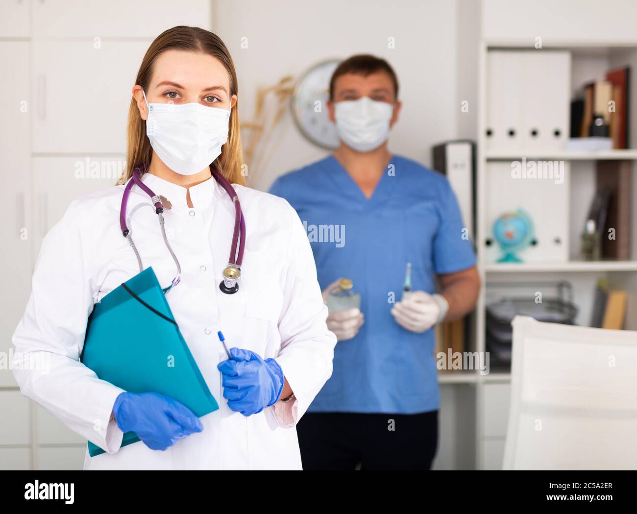 Young woman general practitioner in white lab coat and face mask ...