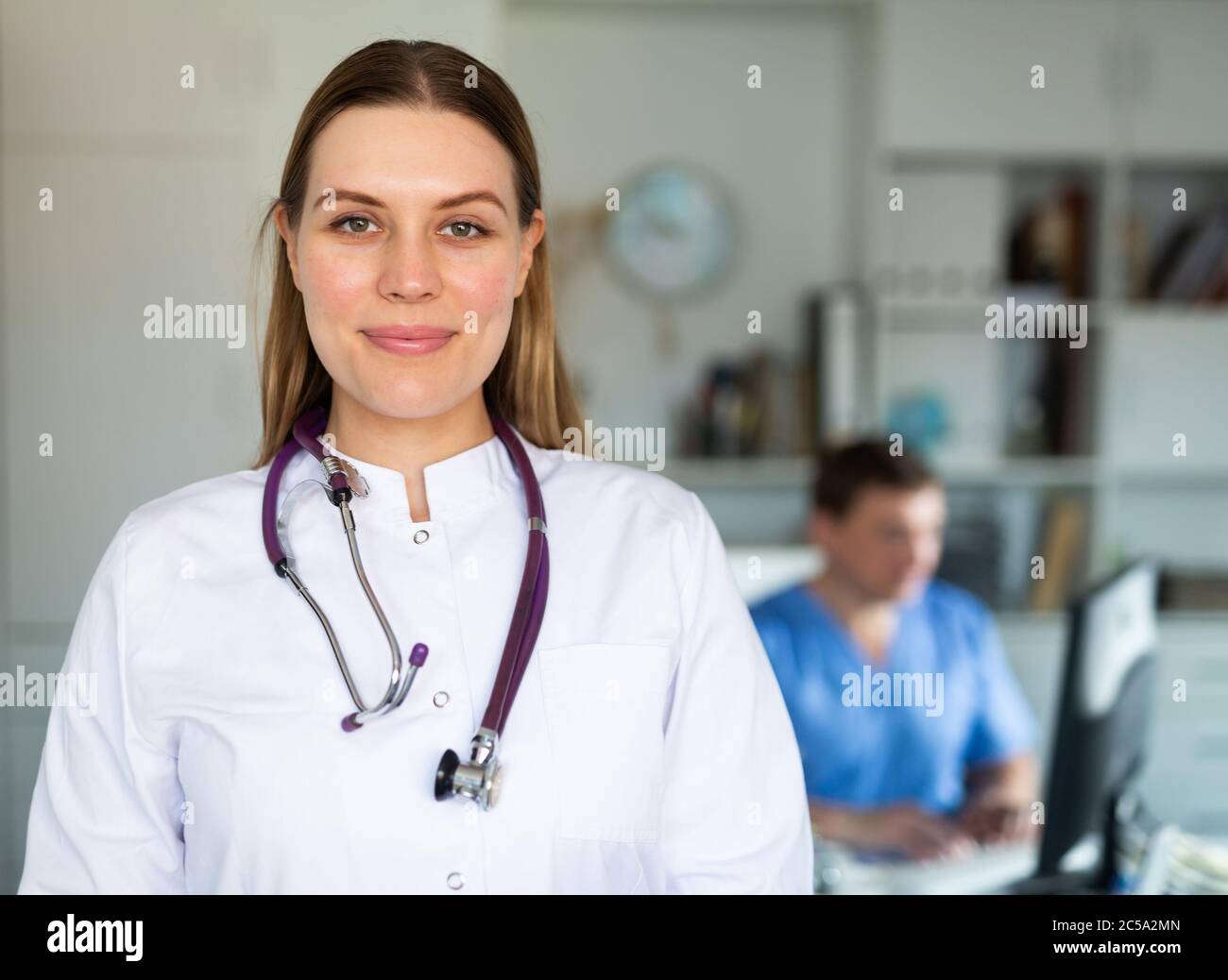Portrait of female doctor in lab coat holding clipboard with medical ...