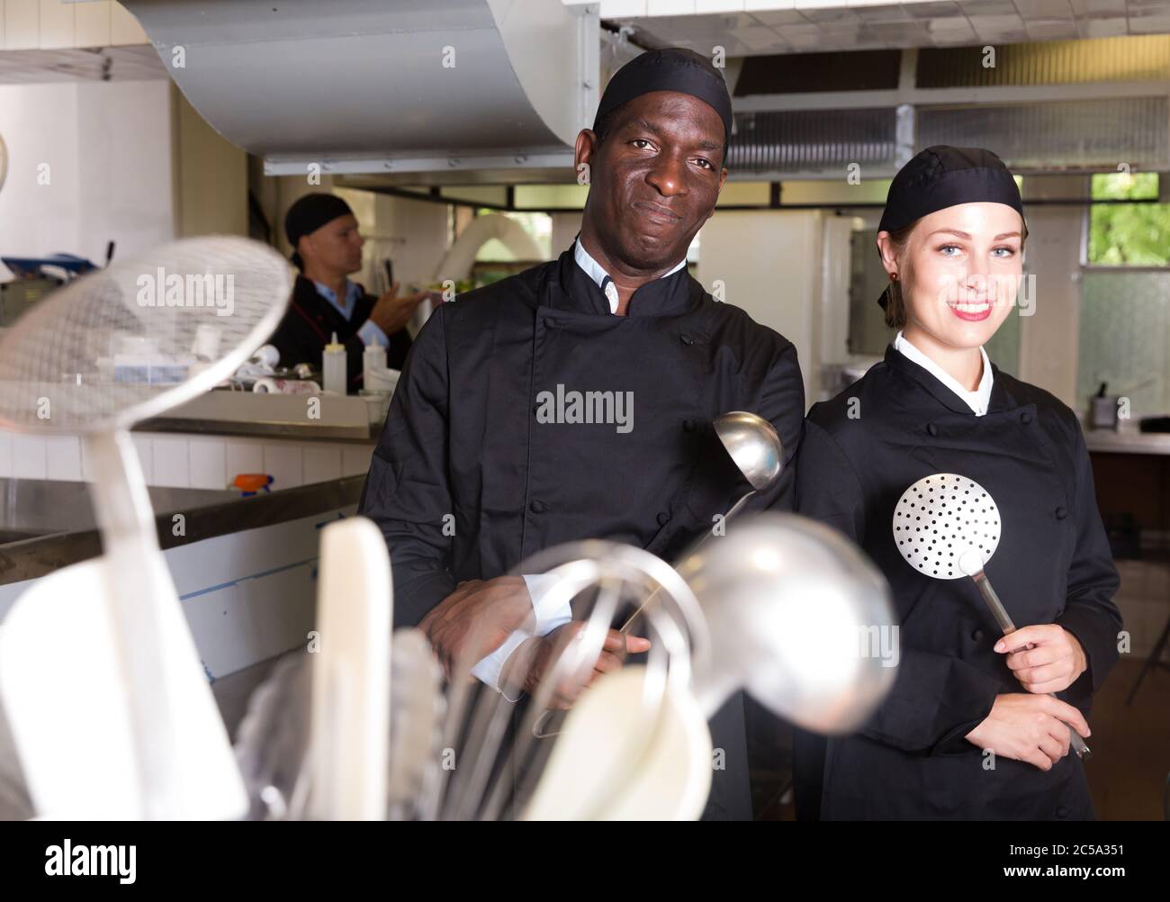 Portrait of two smiling confident chefs posing together in modern ...