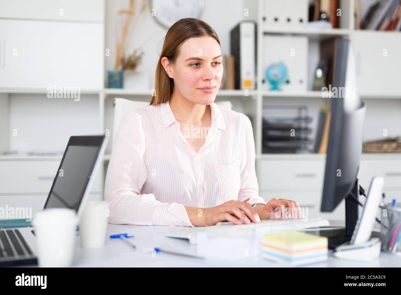 Successful young business woman using computer at workplace Stock Photo ...