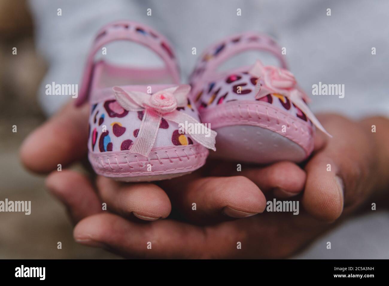 Someone holding a pair of cute, pink-colored baby shoes with brown dots ...
