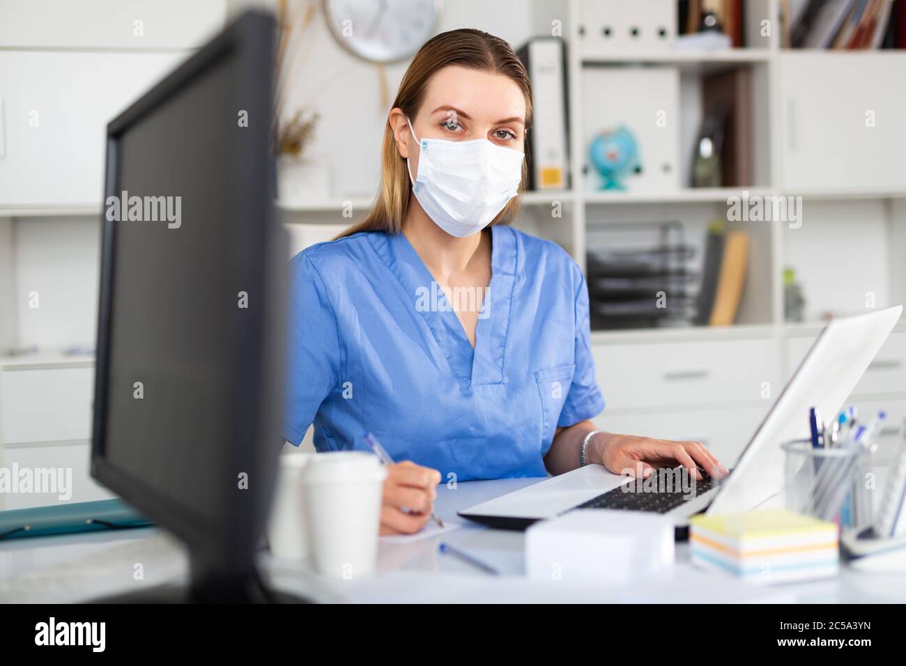 Medical female worker enters patient data into laptop Stock Photo - Alamy
