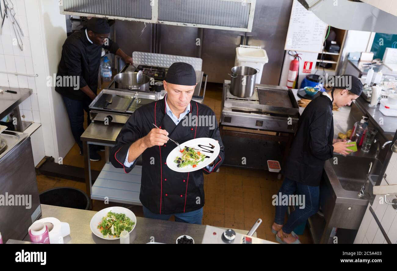 Staff of restaurant with head chef working together in kitchen Stock ...