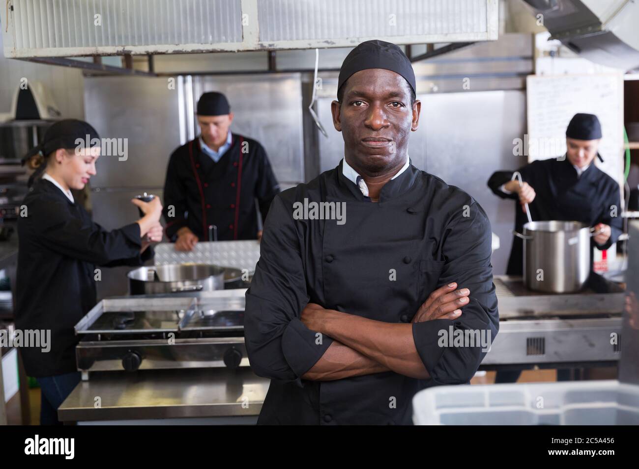 Confident African American chef of restaurant posing with arms crossed ...