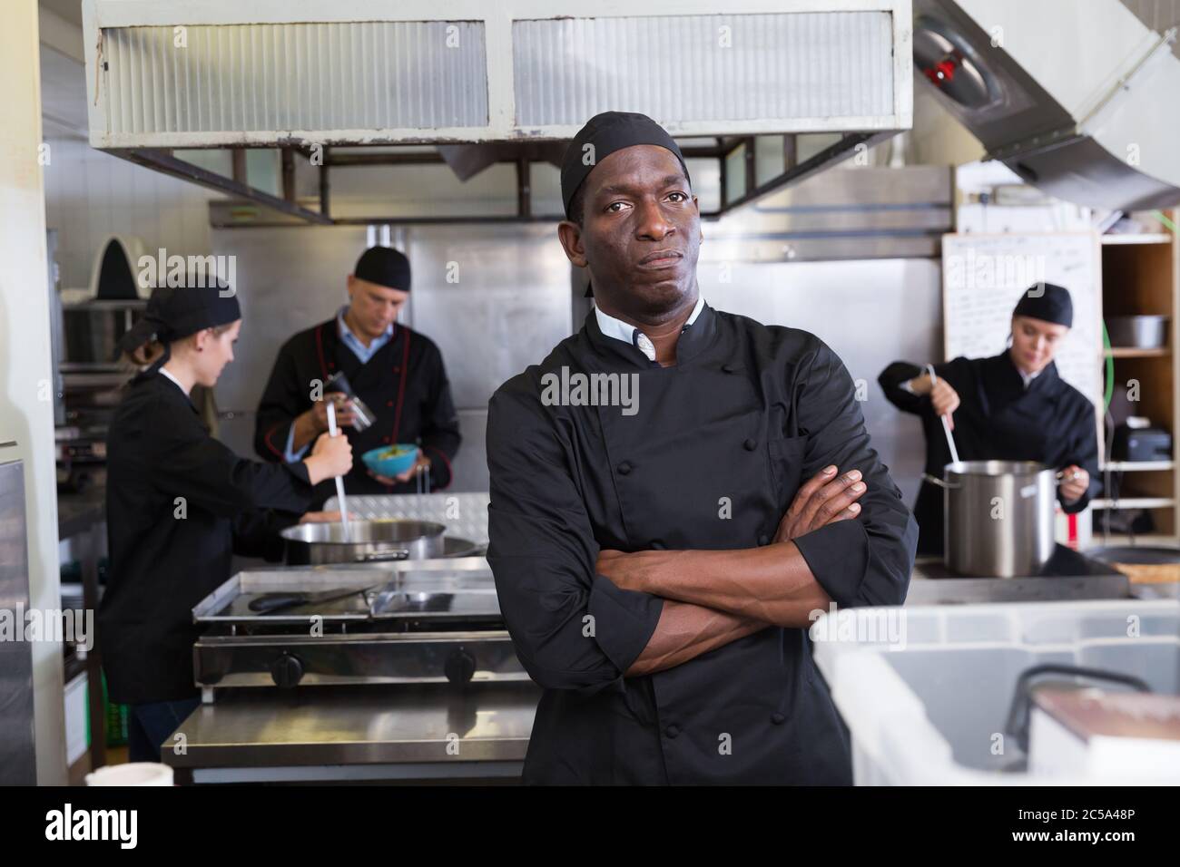 Confident African American chef of restaurant posing with arms crossed ...