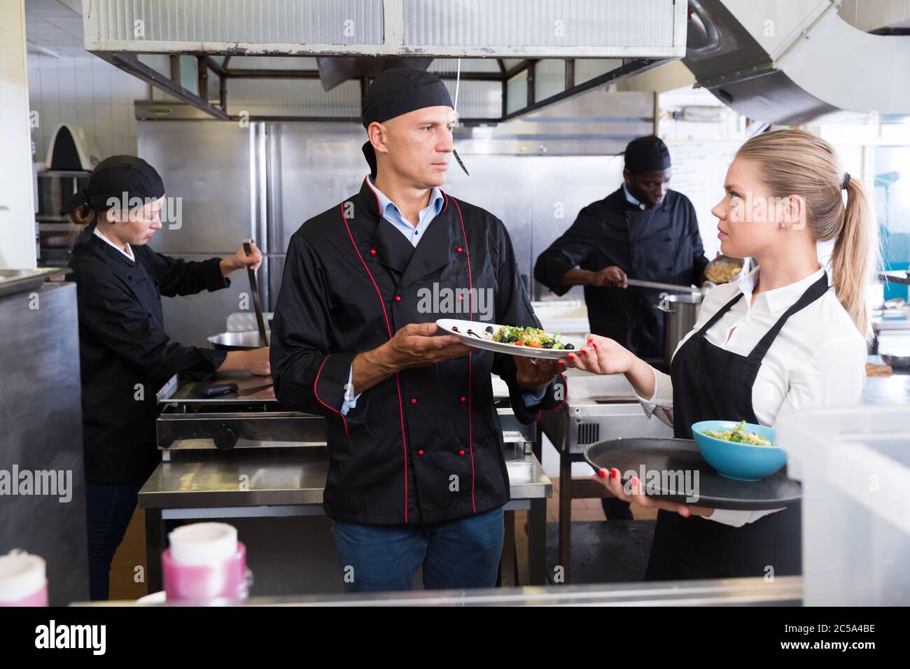 Head chef checking dishes in kitchen of restaurant before serving ...