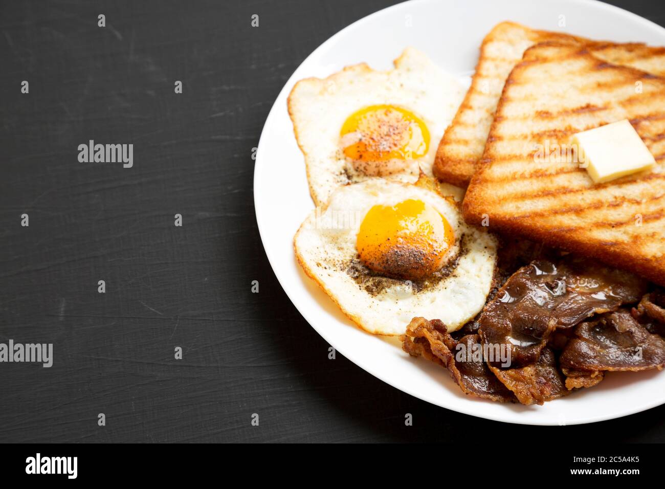 Homemade Healthy Sunnyside Eggs Breakfast on a white plate on a black ...
