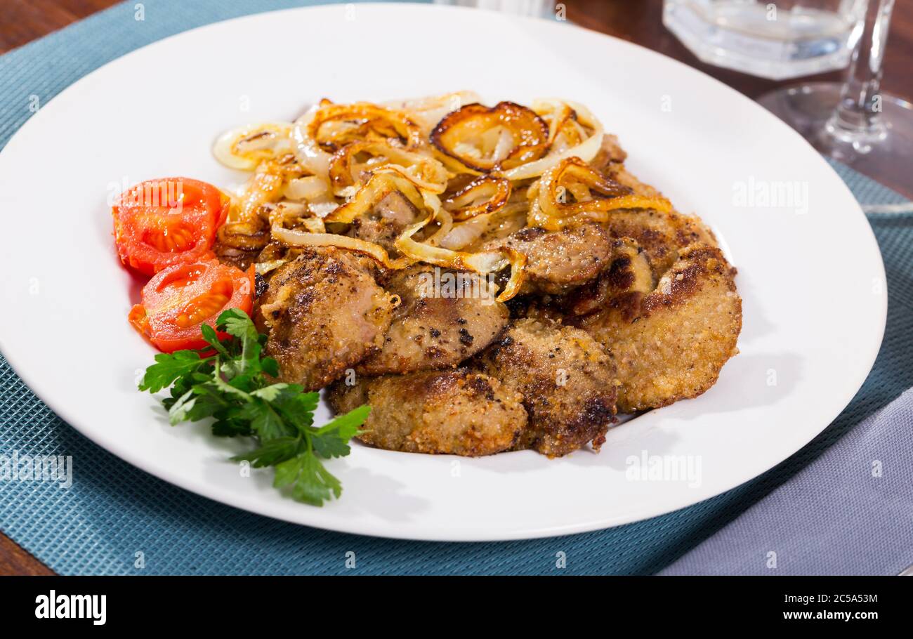 Roasted rabbit liver served with fried onion, fresh tomato and greens ...