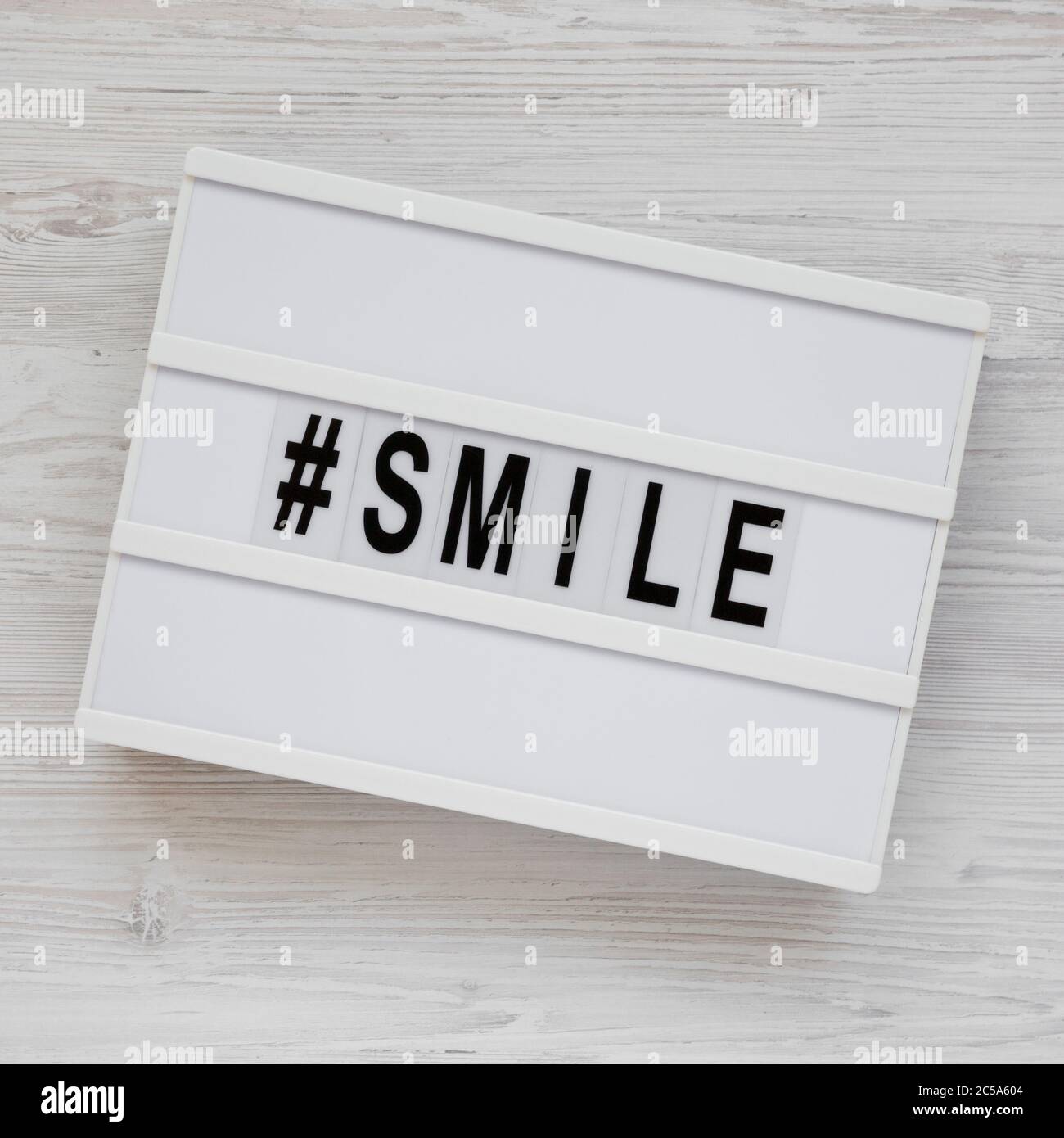 'Smile' word on a lightbox on a white wooden background, top view. Flat ...