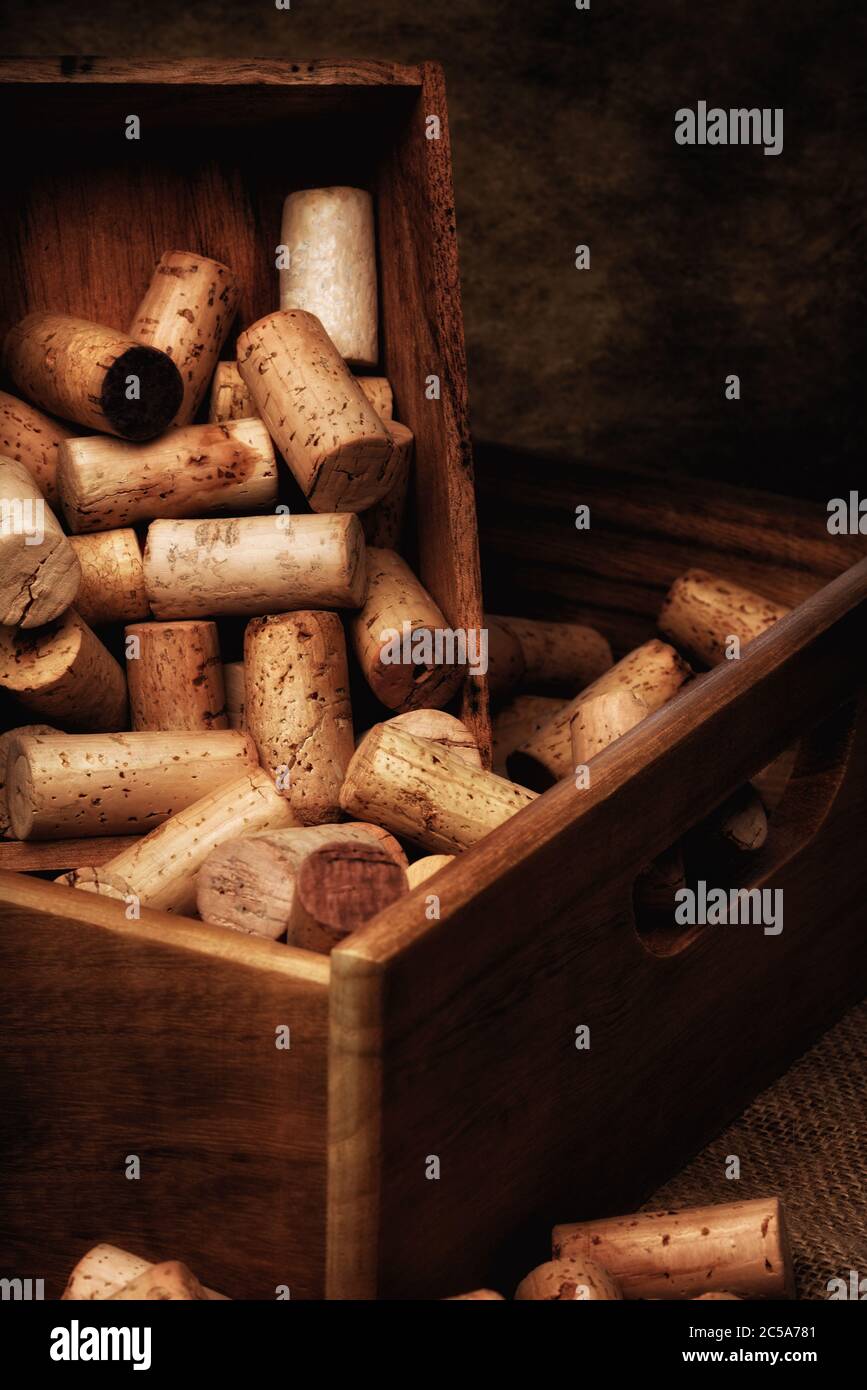 Wooden boxes full of used wine corks with strong warm side light ...