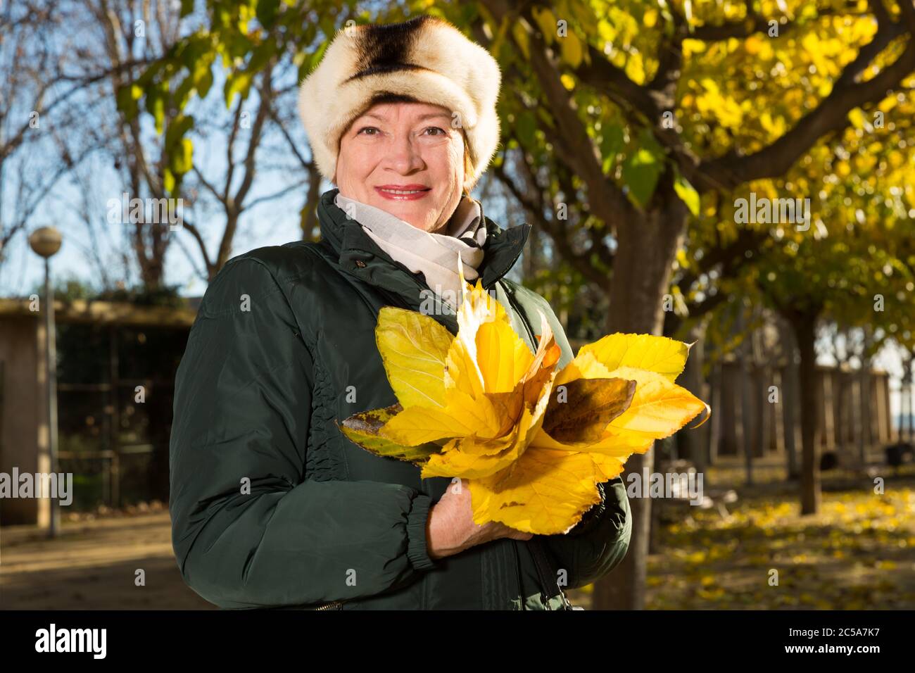 Closeup portrait of happy pleasant mature woman enjoying walk in yellow ...