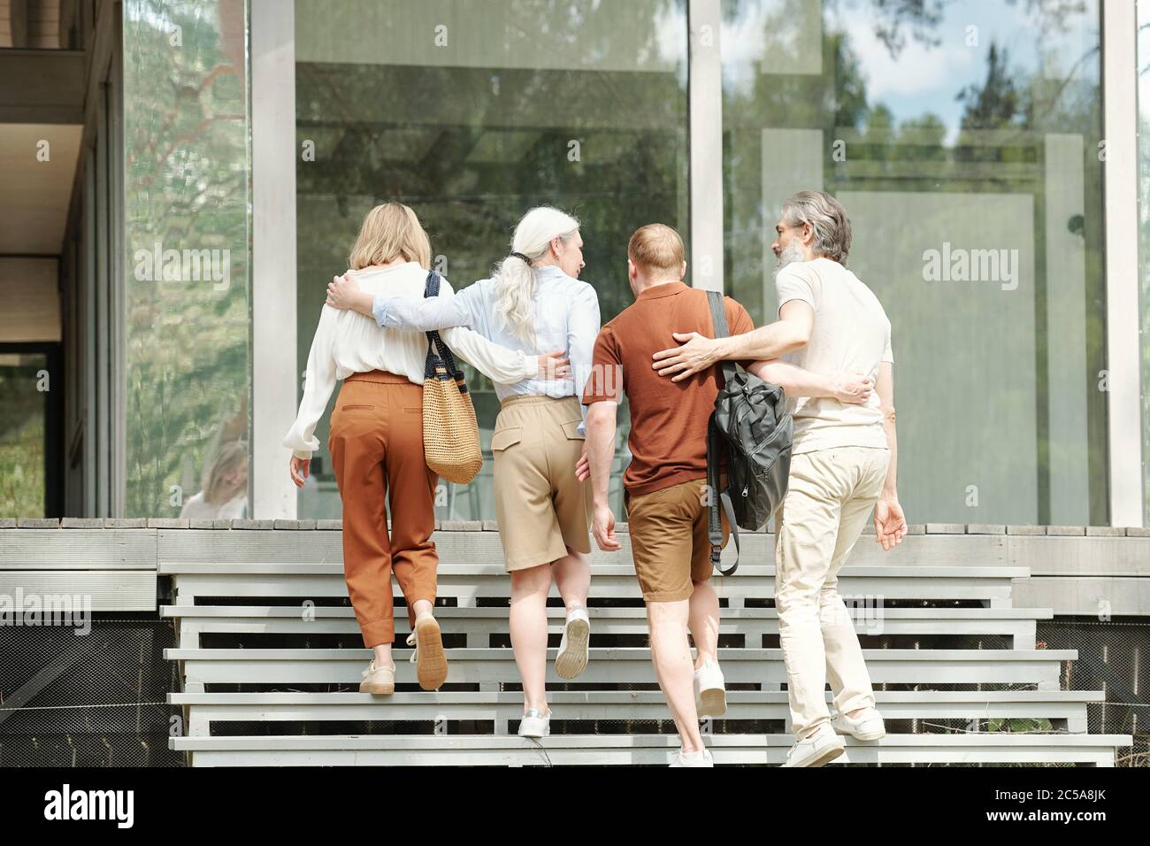 Rear view of senior parents embracing adult son and daughter while ...