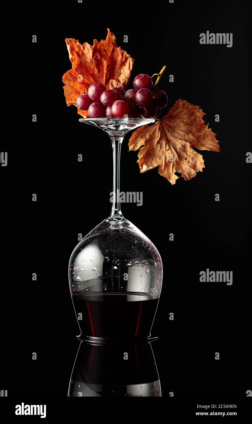 Inverted wine glass with red wine on a black reflective background ...