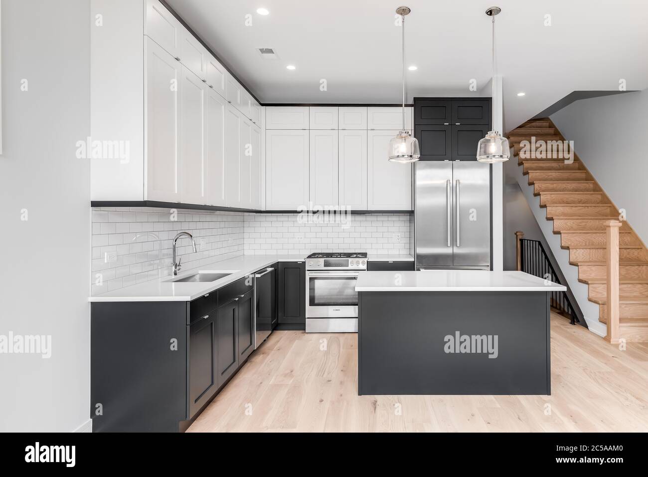 A modern kitchen with white and black cabinets, stainless steel Bosch ...