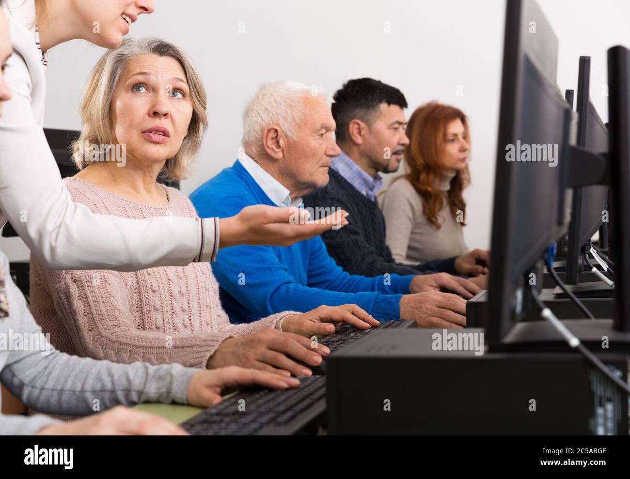 Side view of young businesswoman helping to older coworkers, pointing ...