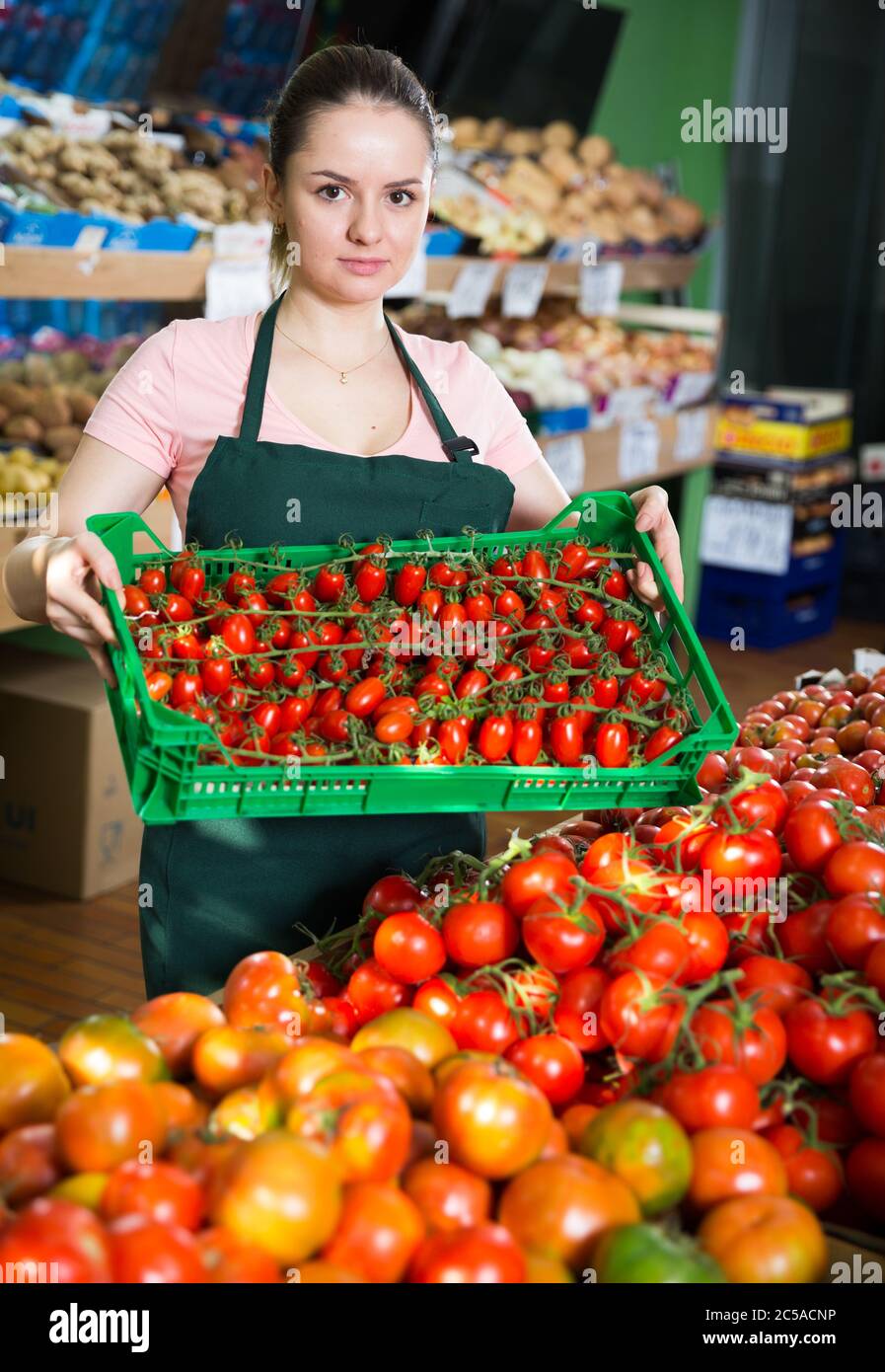 Portrait of smiling salesgirl in store with crate filled with fresh ...
