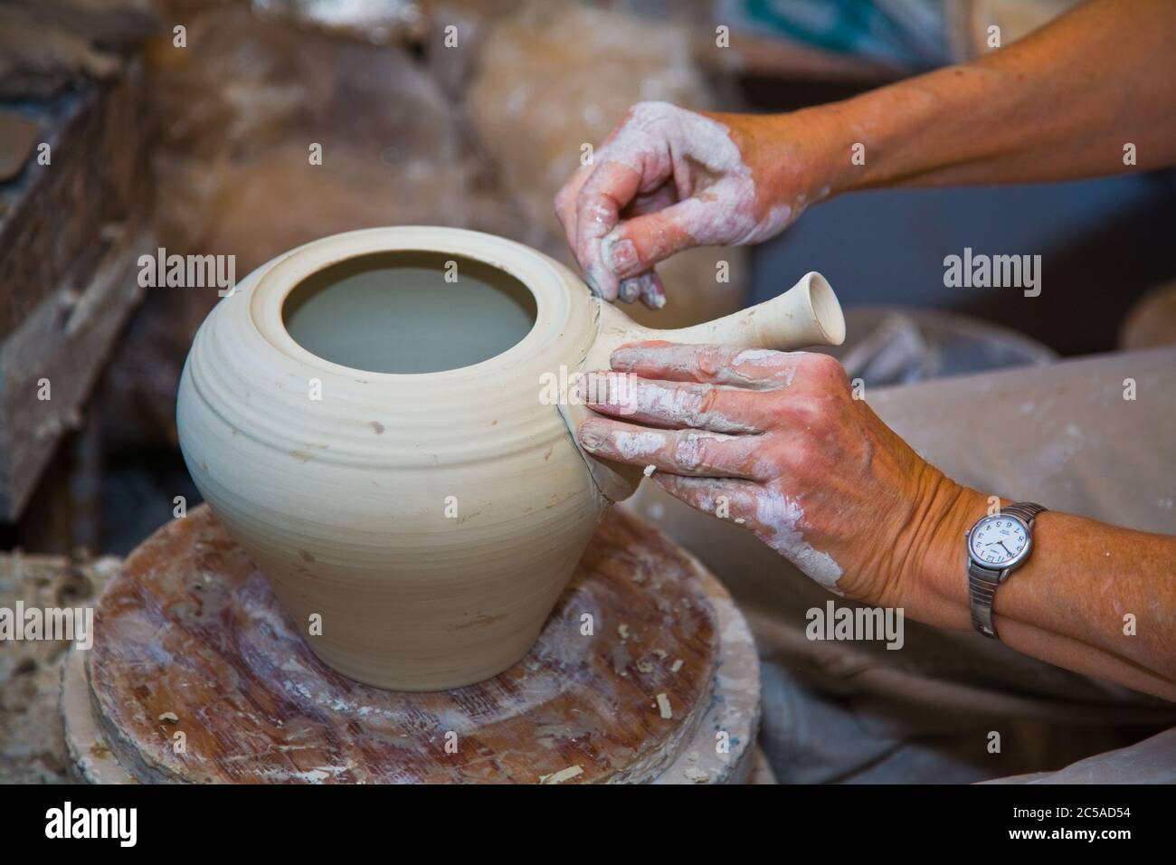 Potter fixing a spout to a clay teapot on a wheel Stock Photo - Alamy