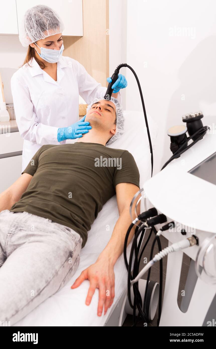Focused woman cosmetologist giving electroporation procedure to ...
