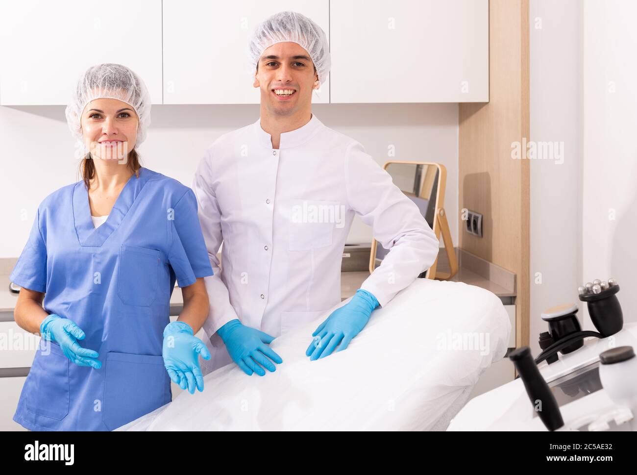 Portrait of young confident man and woman doctors in interior of clinic ...
