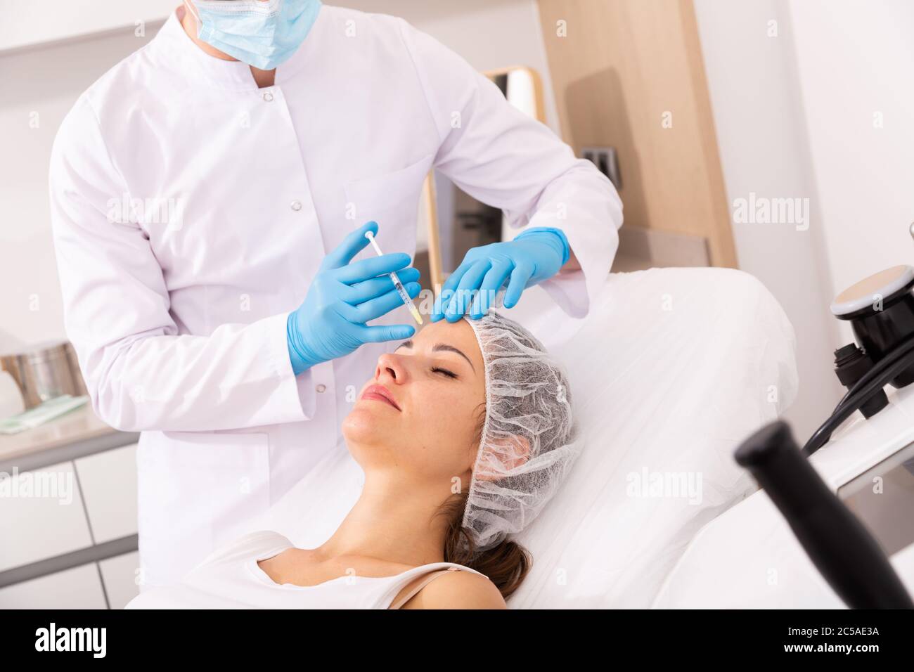 Young woman patient of beautician receiving rejuvenating facial ...