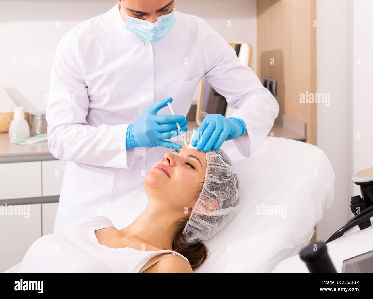 Young woman patient of beautician receiving rejuvenating facial ...