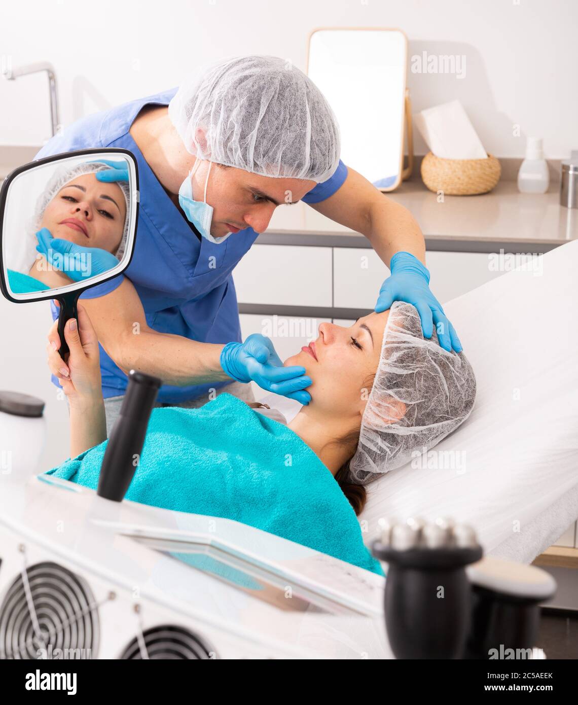 Expert male cosmetologist giving consultation to young woman patient ...
