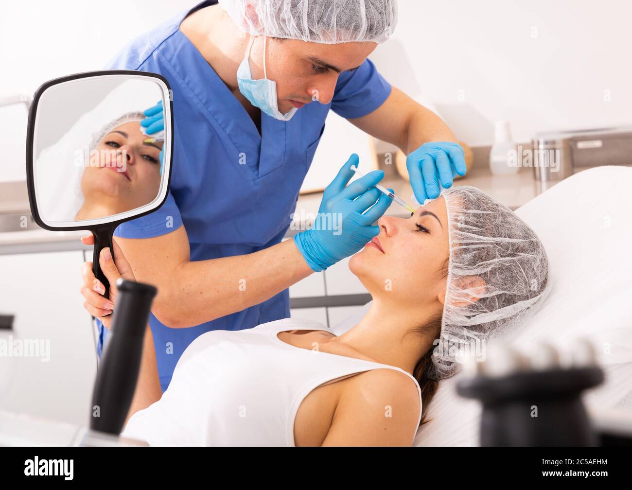 Confident male cosmetologist filling female wrinkles by hyaluronic acid ...