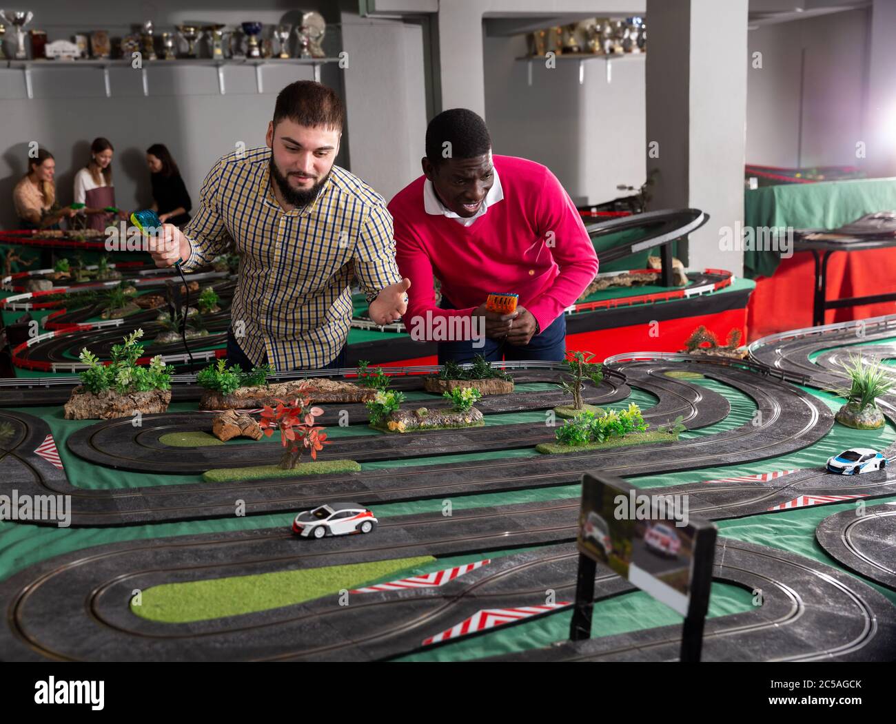Two men with remote control playing race car models on the track Stock ...