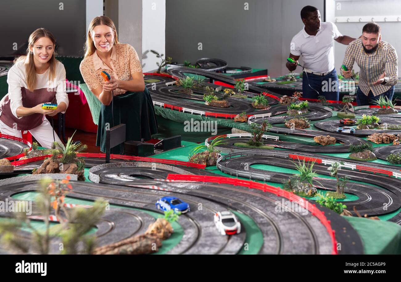 Two young couples playing with slot car model racing track Stock Photo ...