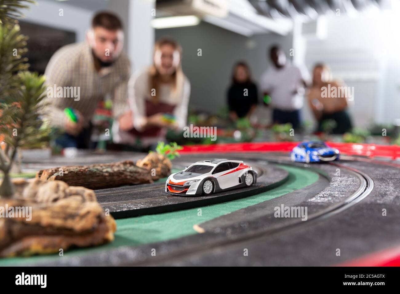 Models of race cars on the track in game room, group of players drive ...