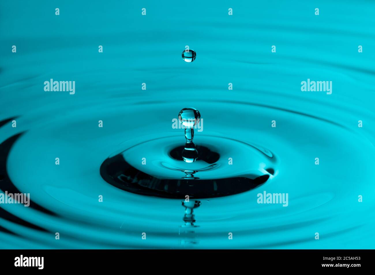 Perfect water drop splashing into smooth water causing ripples Stock ...