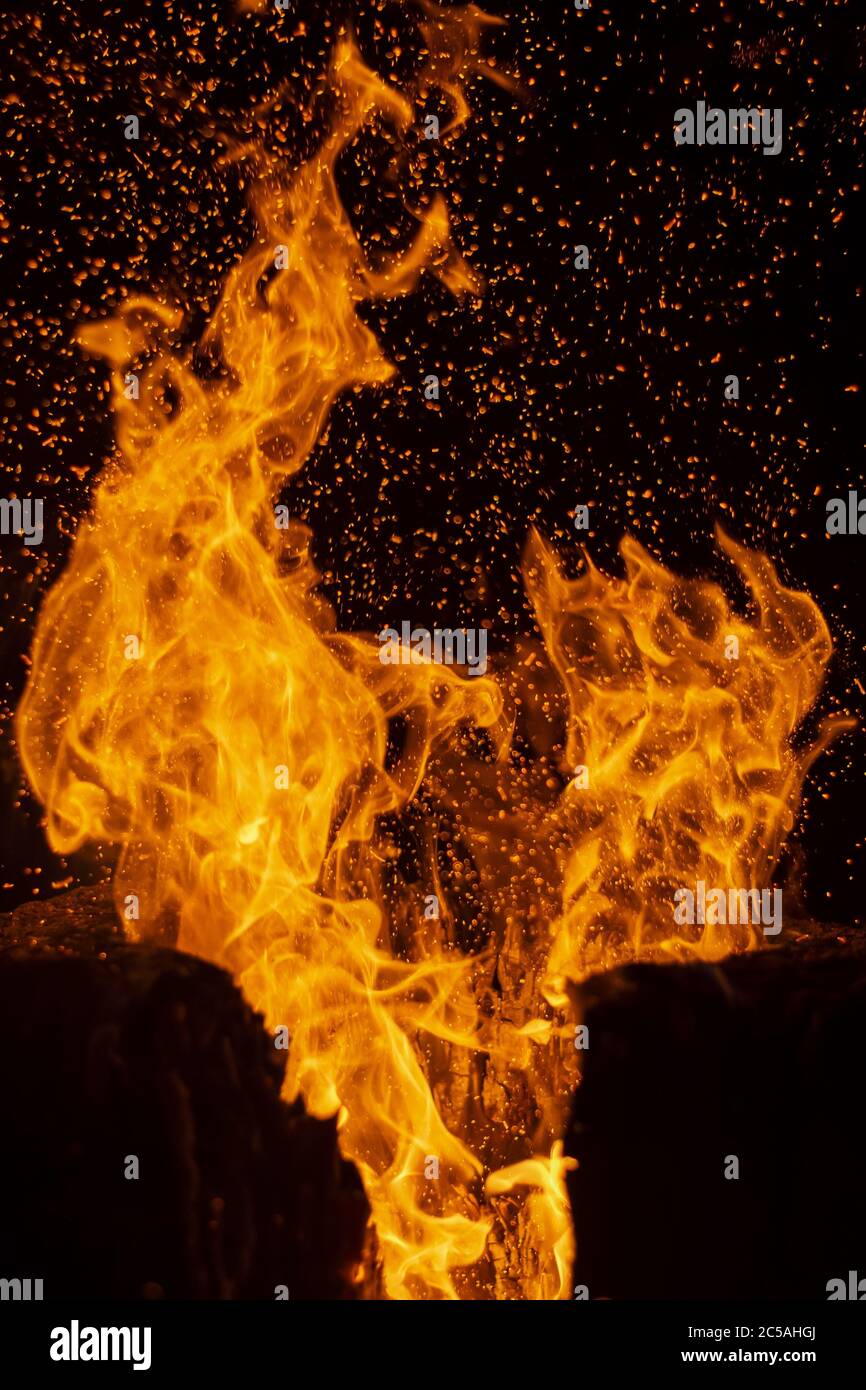 Vertical image of a burning log with flying sparks creating a fiery ...