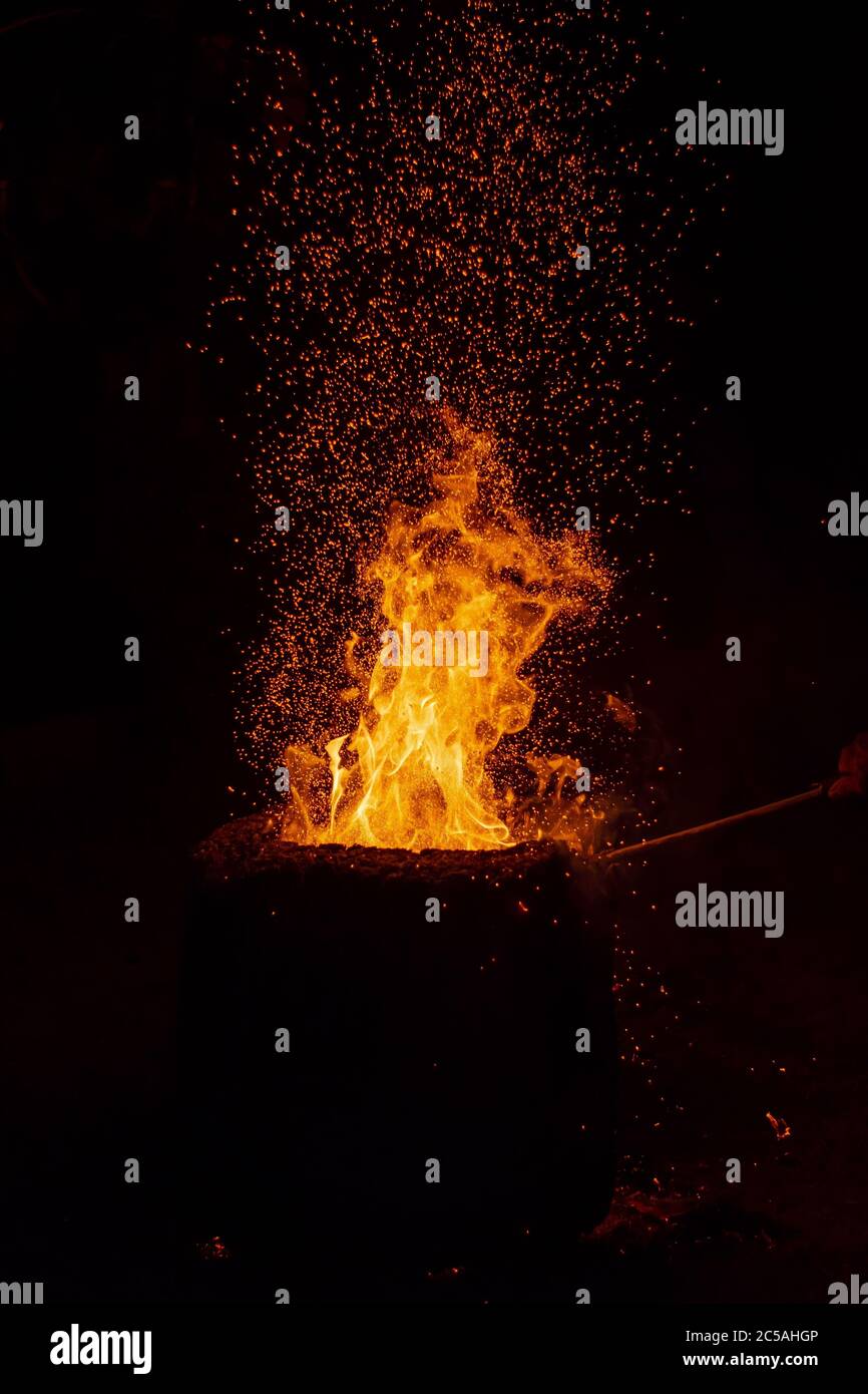 Vertical image of a burning log with flying sparks creating a fiery ...