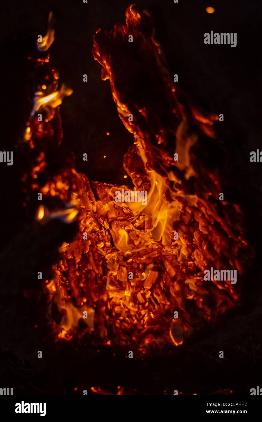 Vertical image of embers of a burning log creating a fiery background ...