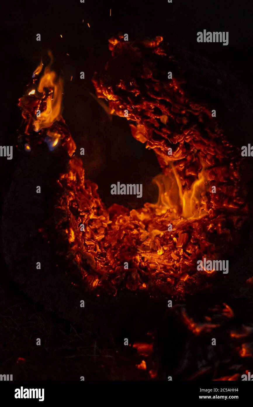 Vertical image of embers of a burning log creating a fiery background ...