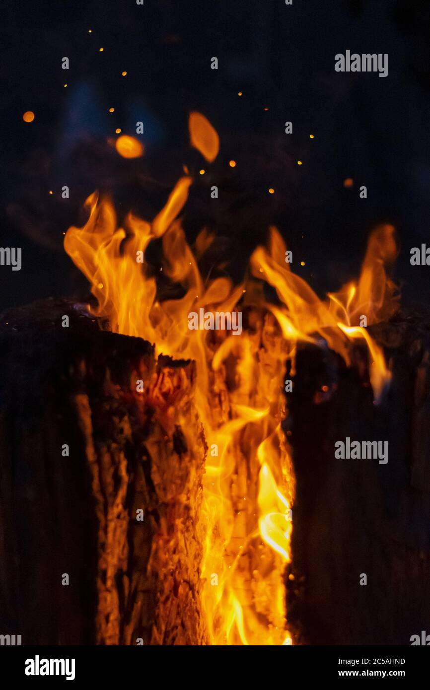 Closeup of glowing log embers and flames creating a fiery abstract ...