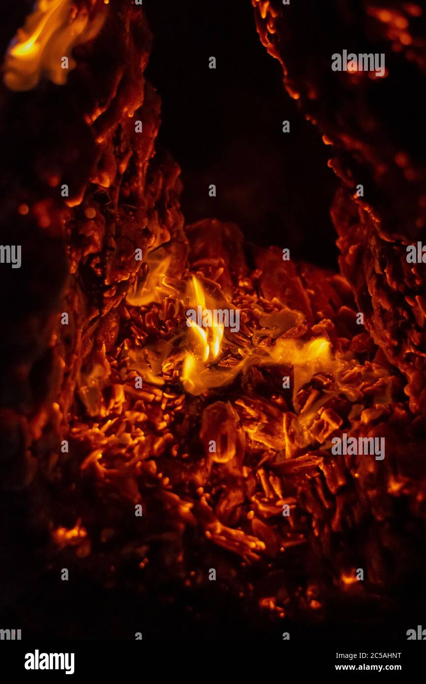 Vertical image of embers of a burning log creating a fiery background ...